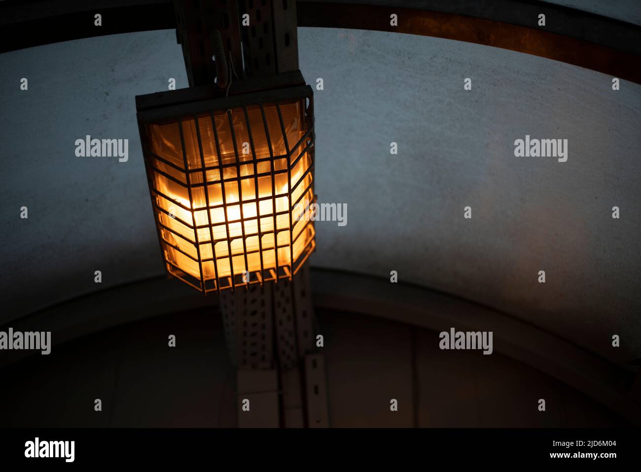 Lamp behind bars. Dim lamp light. Light system in tunnel. Square light ...