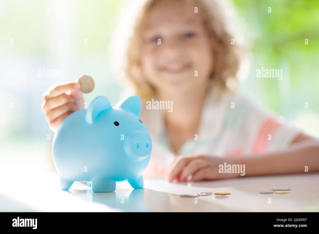 Child putting coin in piggy bank. Kids learn about money. Savings and ...