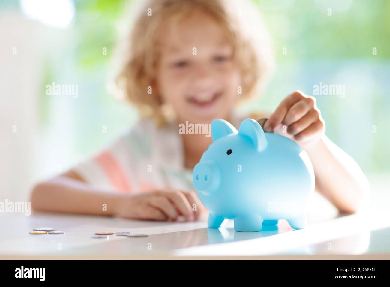 Child putting coin in piggy bank. Kids learn about money. Savings and ...