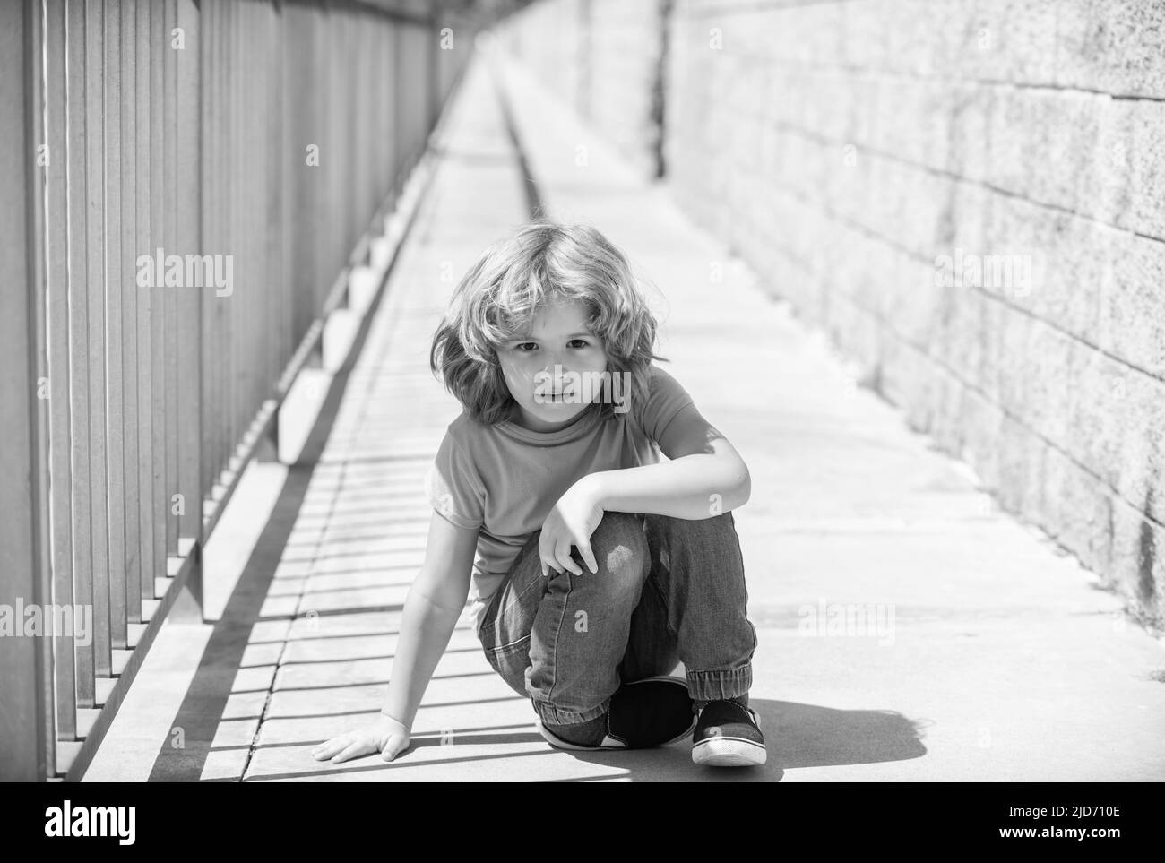Boy kid take rest sitting down on promenade on summer outdoors, resting ...