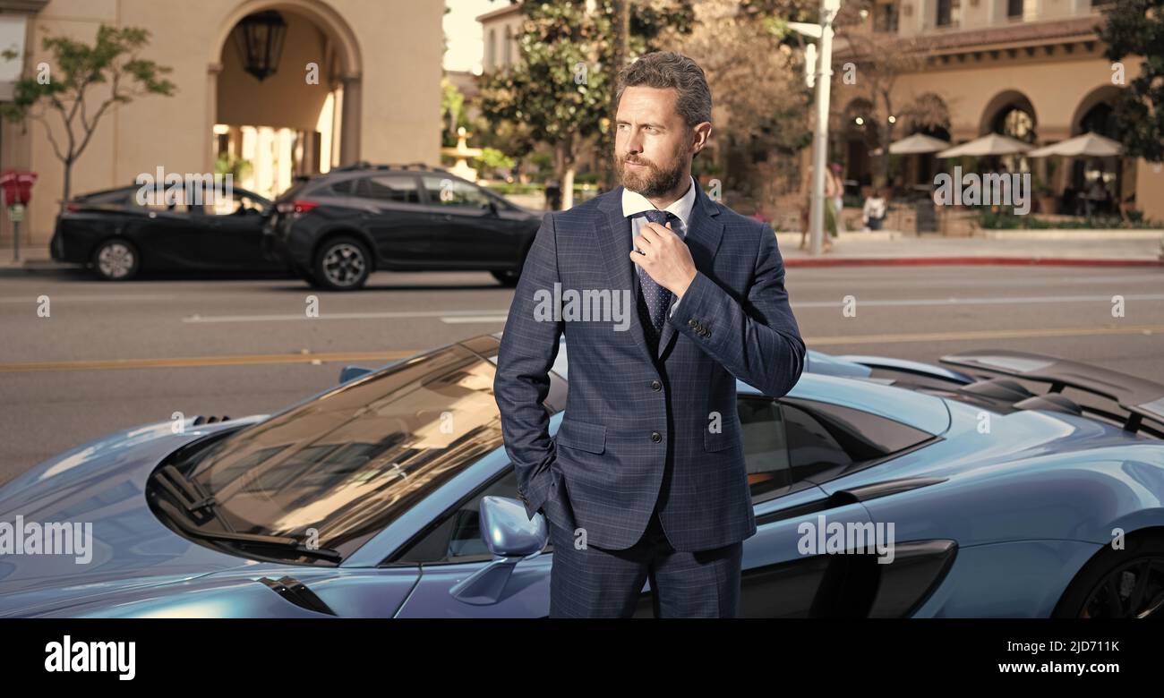 successful dealer in blue business suit at super car outdoor ...