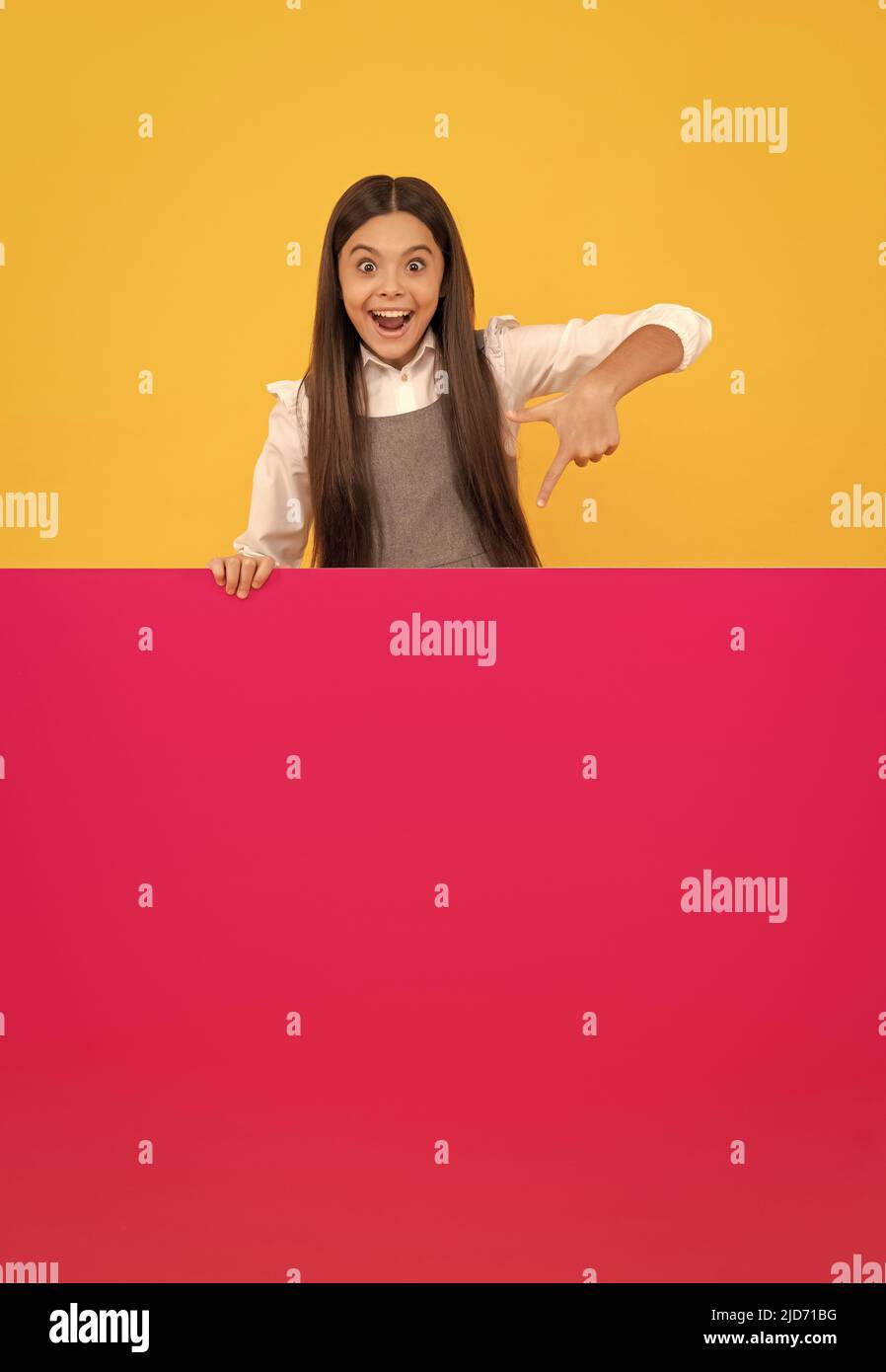 amazed kid pointing finger on blank pink paper sheet for copy space ...