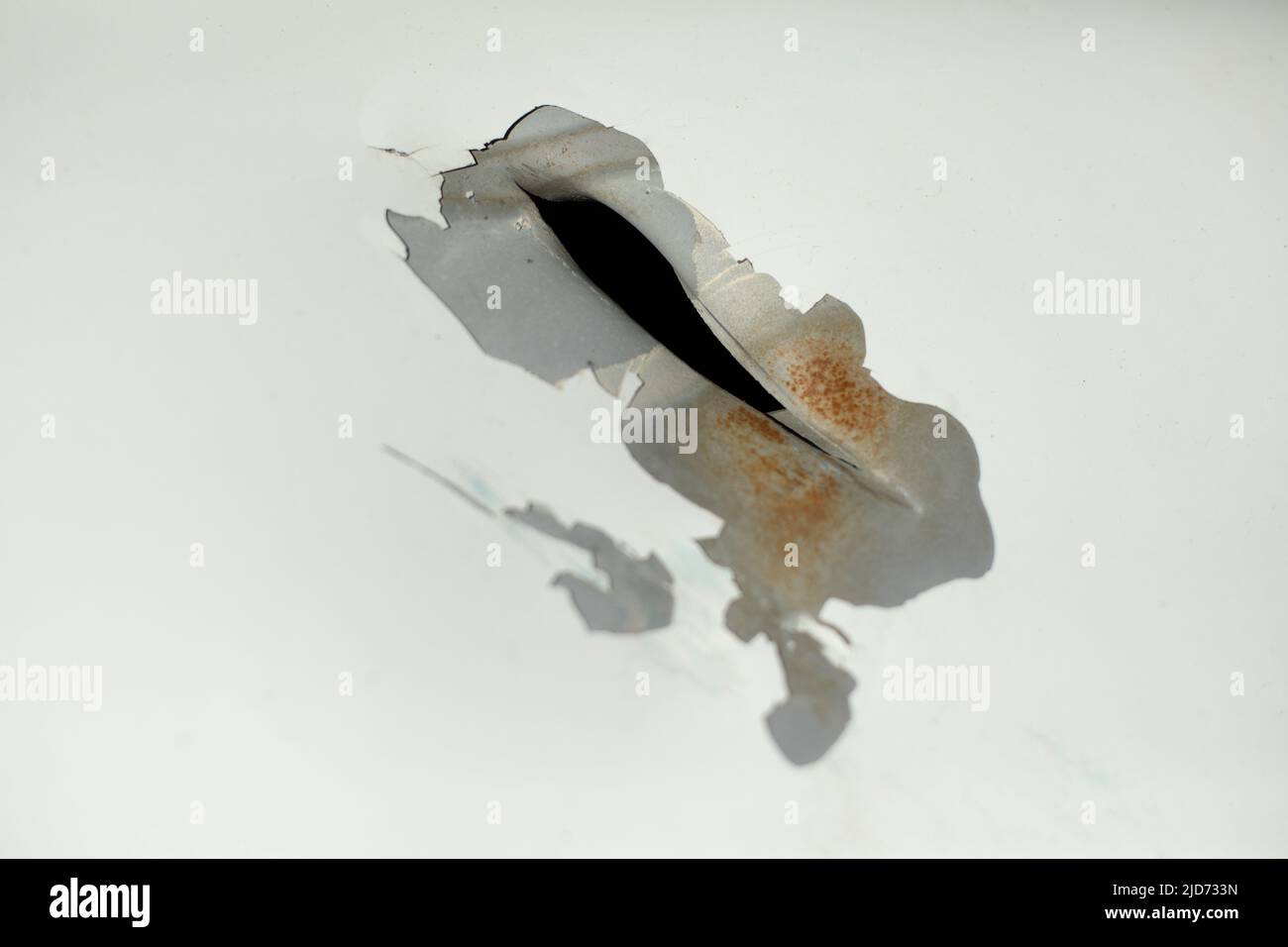 Hole in metal. Damaged steel with white paint. Broken surface of car ...