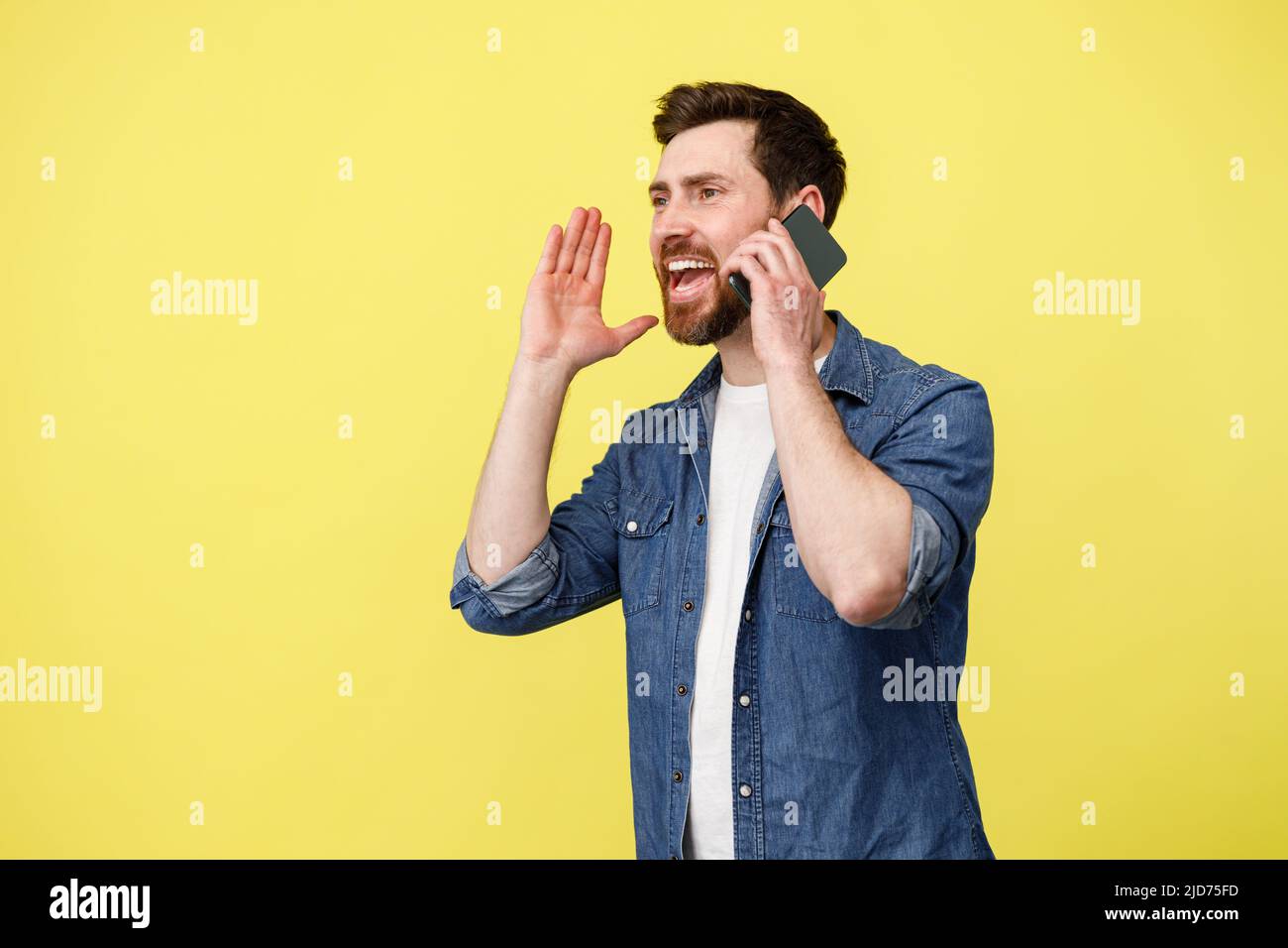 Happy man shouting loudly while talking on the phone and gesturing with ...