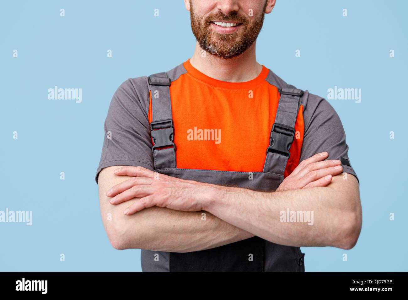 Unrecognizable smiling workerman in uniform with crossed hands looking ...