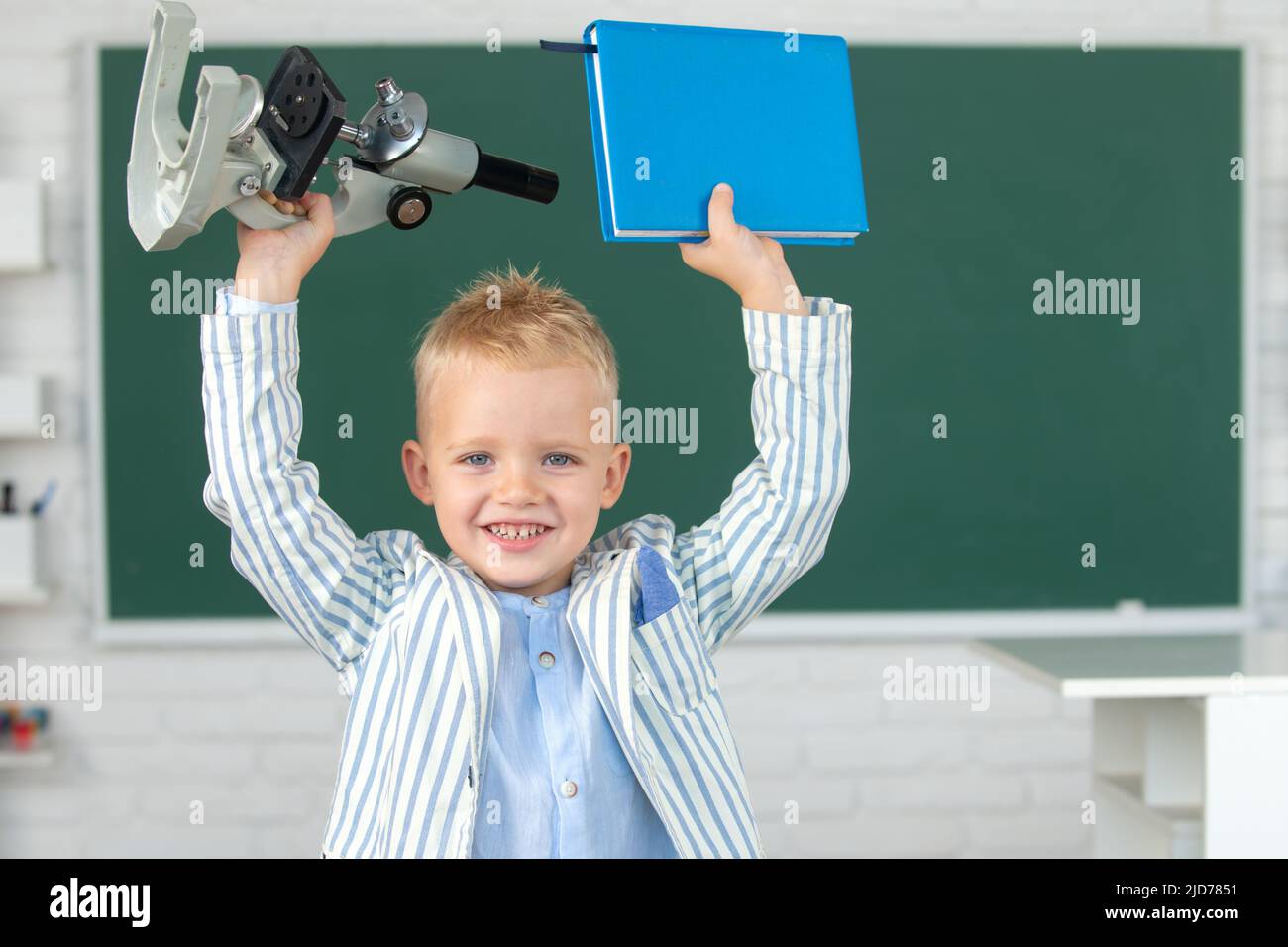 Amazed school boy with microscope and book. Child at school. Kid is ...