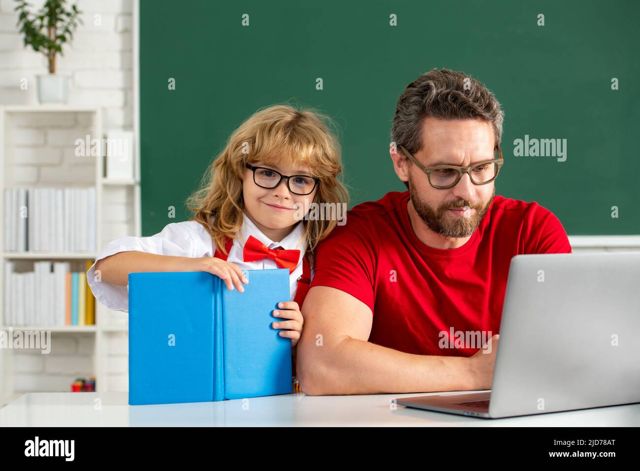 Teacher helping child student pupil from elementary school in classroom ...