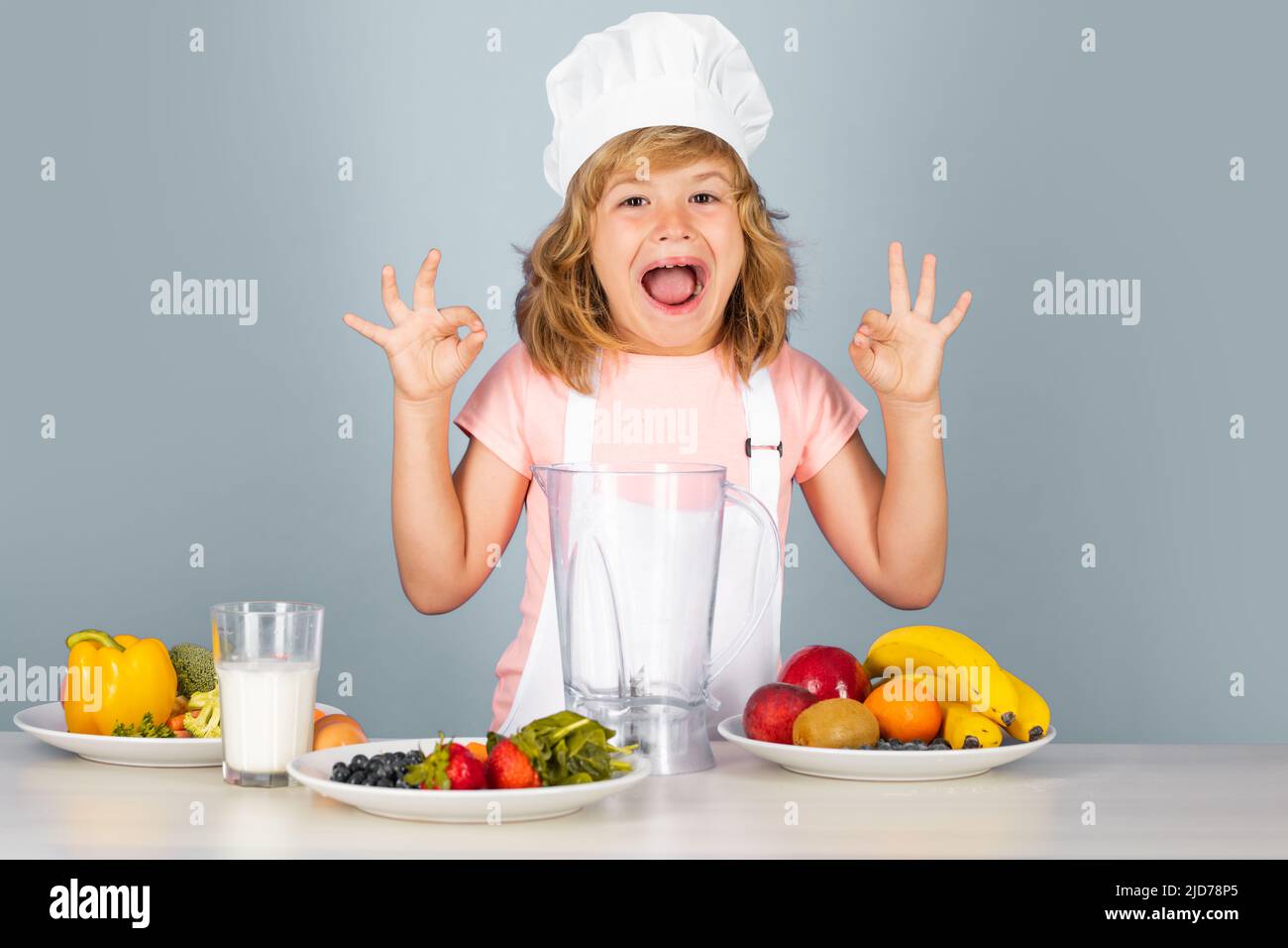 Child chef cook prepares food on isolated grey studio background. Kids ...