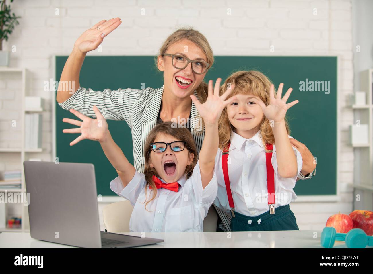 Excited teacher with a school kids learning at laptop computer ...