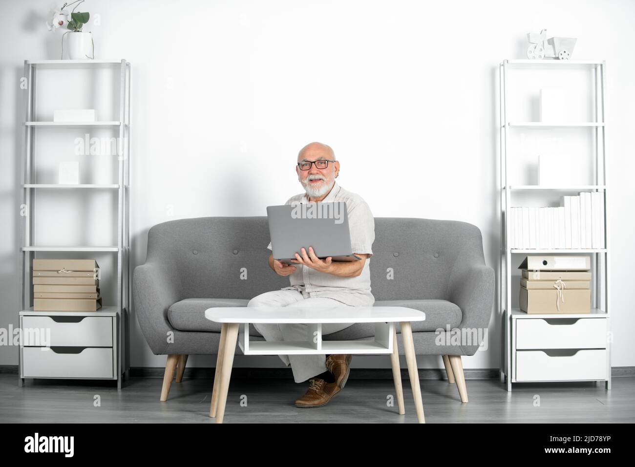 Portrait of senior office worker with a laptop. Senior man with a gray ...