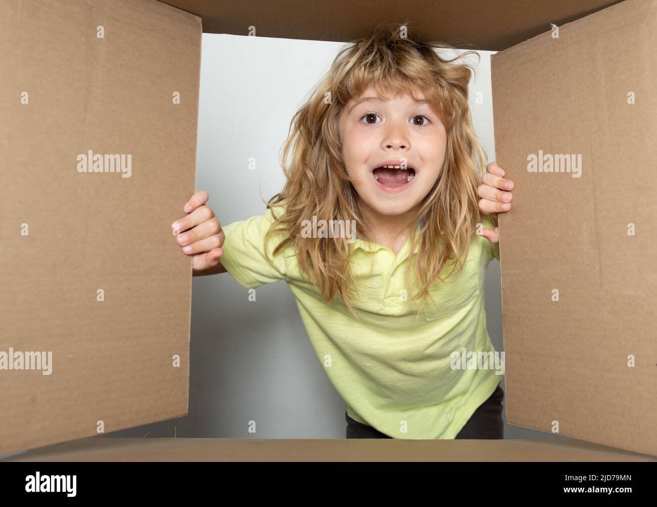 Funny excited child age 9 year unpacking and opening the carton box ...