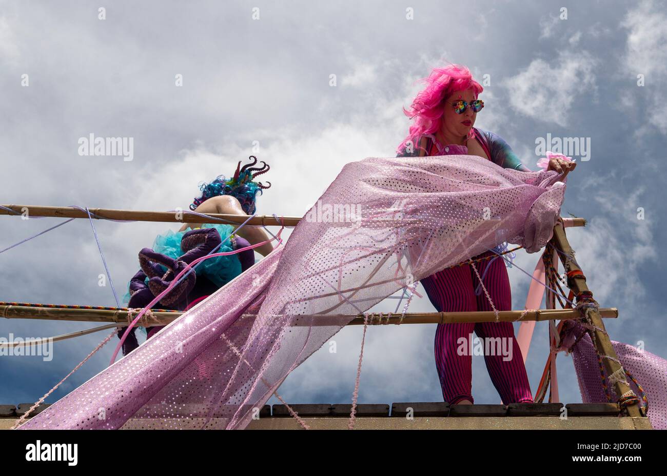 A woman wearing pink hangs a pink cloth from a parade float. The Coney ...