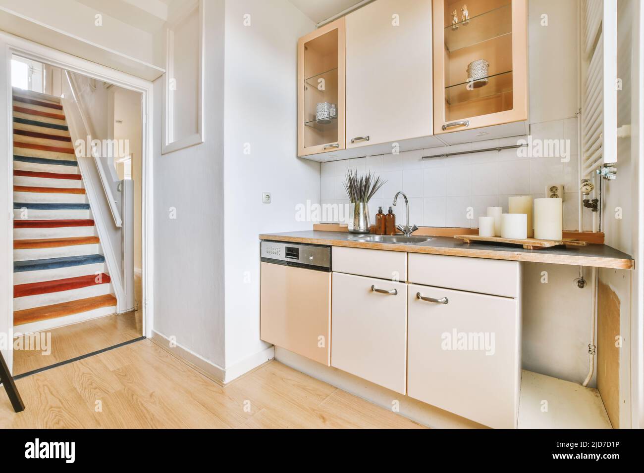 Bright small home kitchen with cabinets and shelves, a sink and a ...