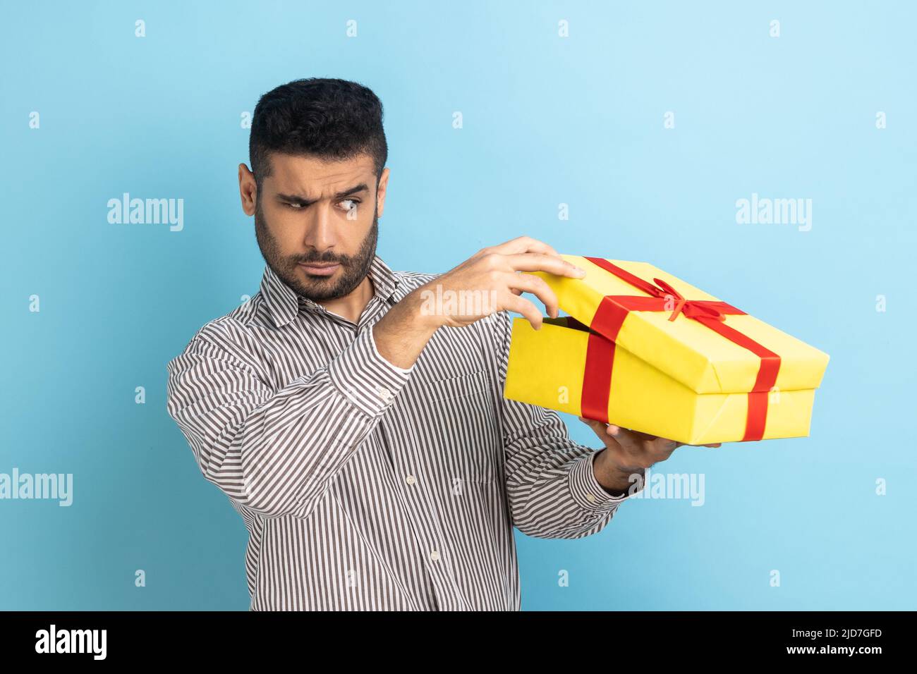 Curious man with beard taking a look inside gift box, unpacking present ...