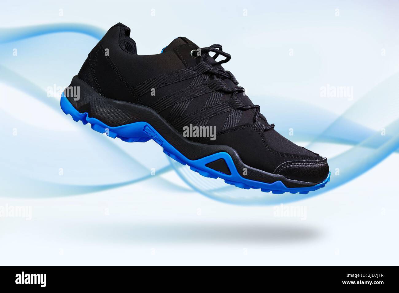 Flying touristic waterproof black and blue man shoe from side on wave ...