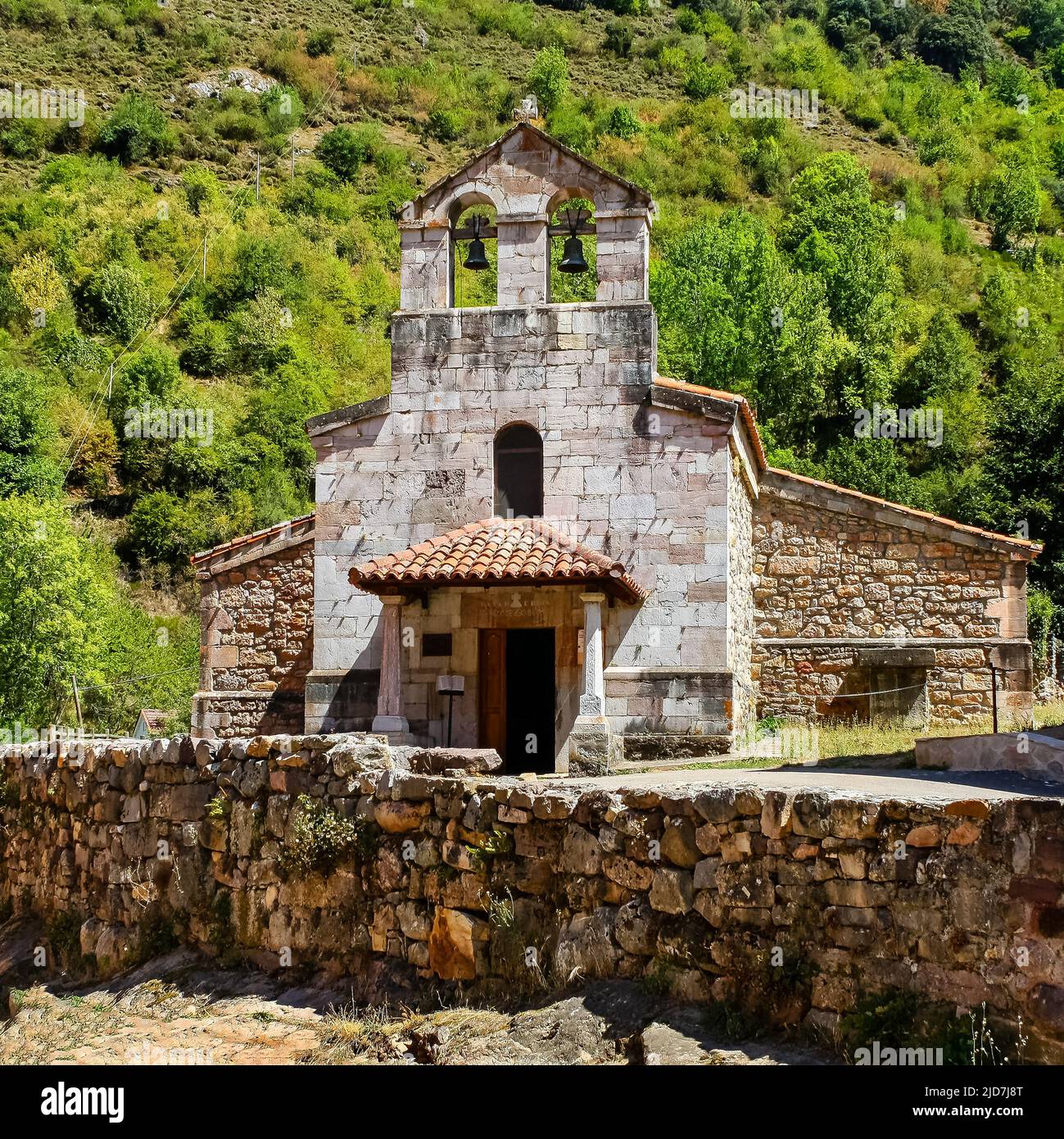 Small stone chapel next to ancient stone wall in the green field ...