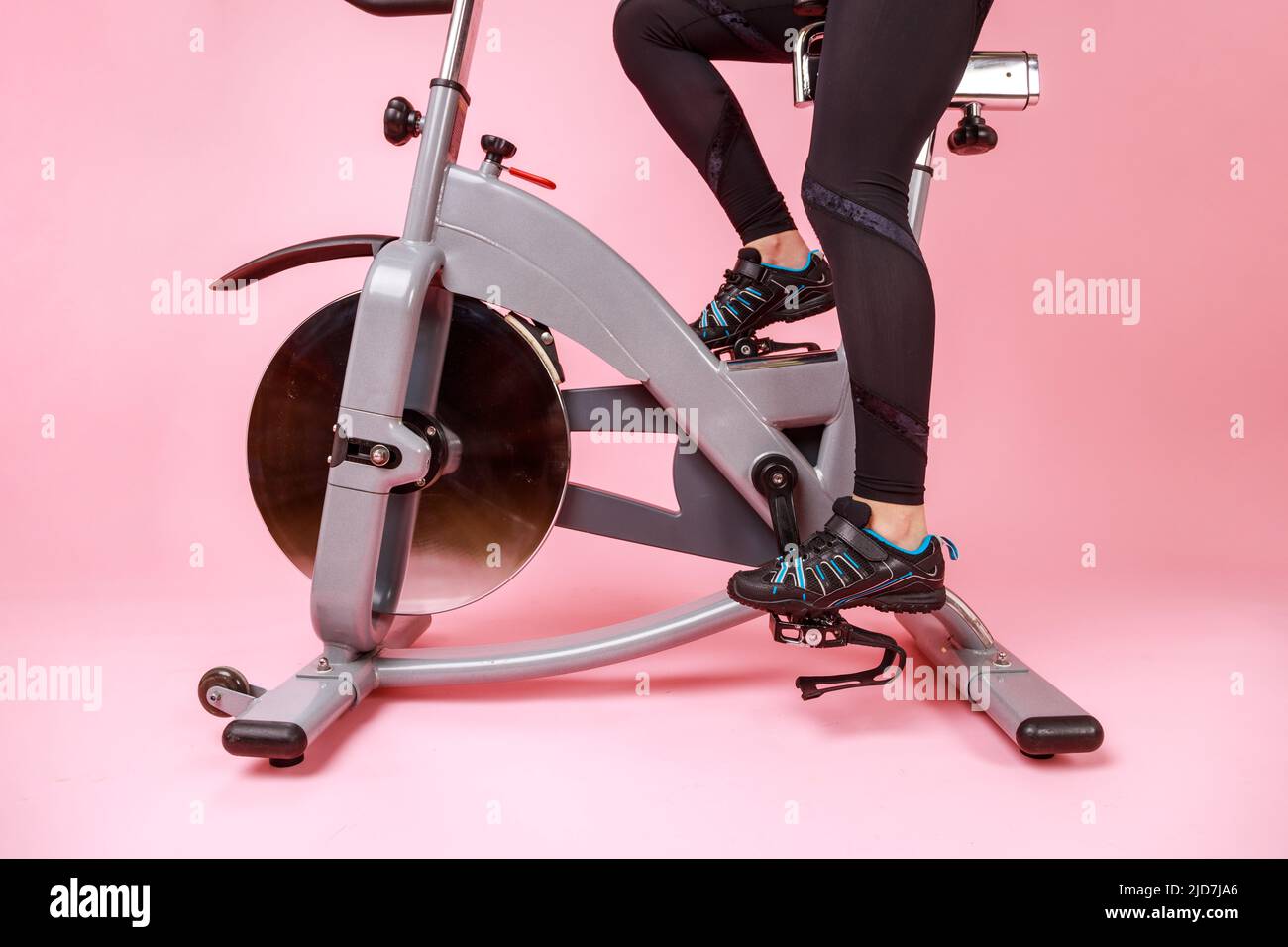 Portrait of the bike simulator and women's legs in black sneakers and ...