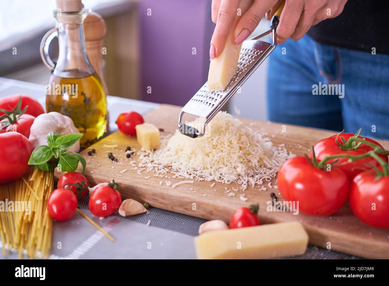 grating parmesan on a wooden gutting board at domestic kitchen Stock ...