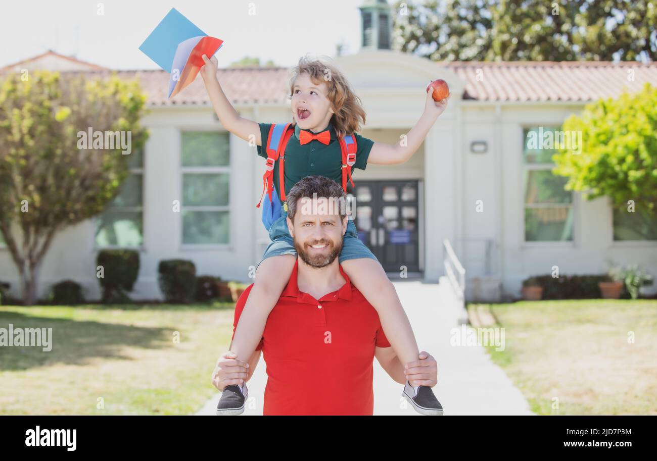 Man and happy amazed child piggyback near school. Father walking son to ...