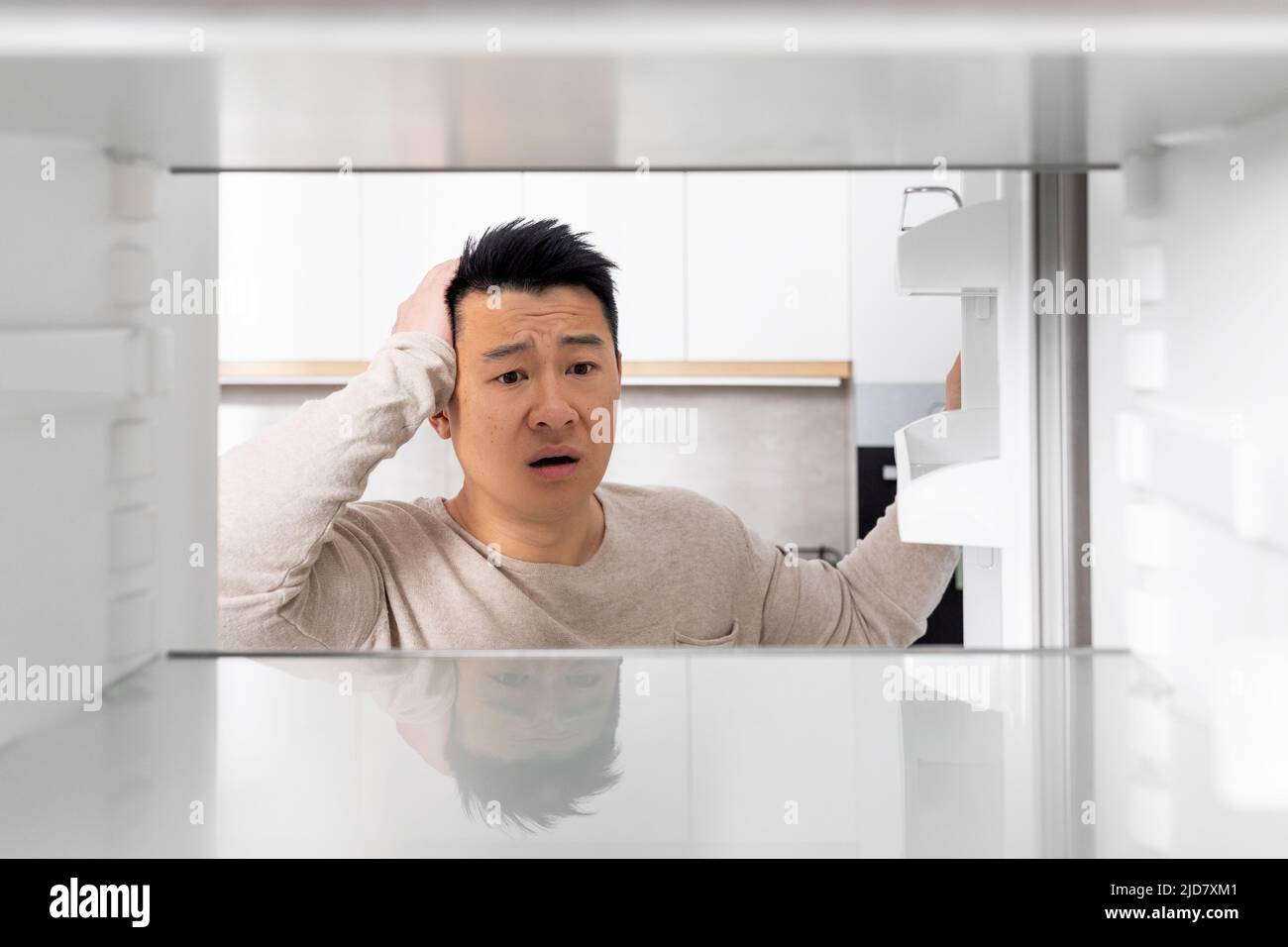 Shocked chinese man looking inside empty fridge Stock Photo - Alamy