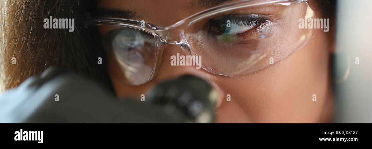A dark-skinned woman looks through a microscope Stock Photo - Alamy