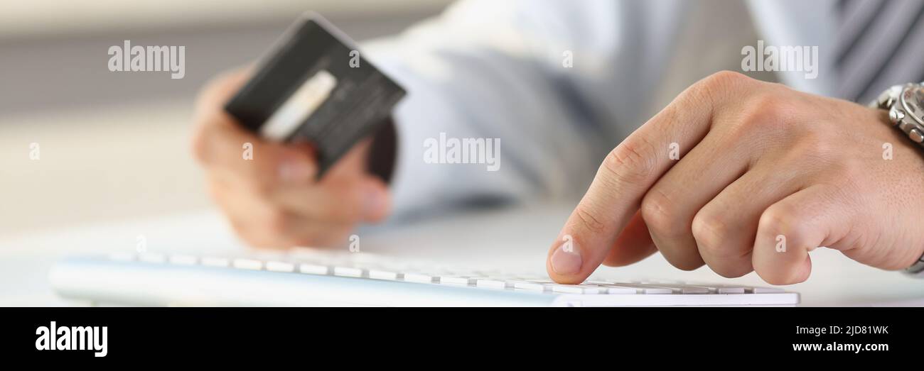 A man with a credit card in his hand is typing on the keyboard Stock ...