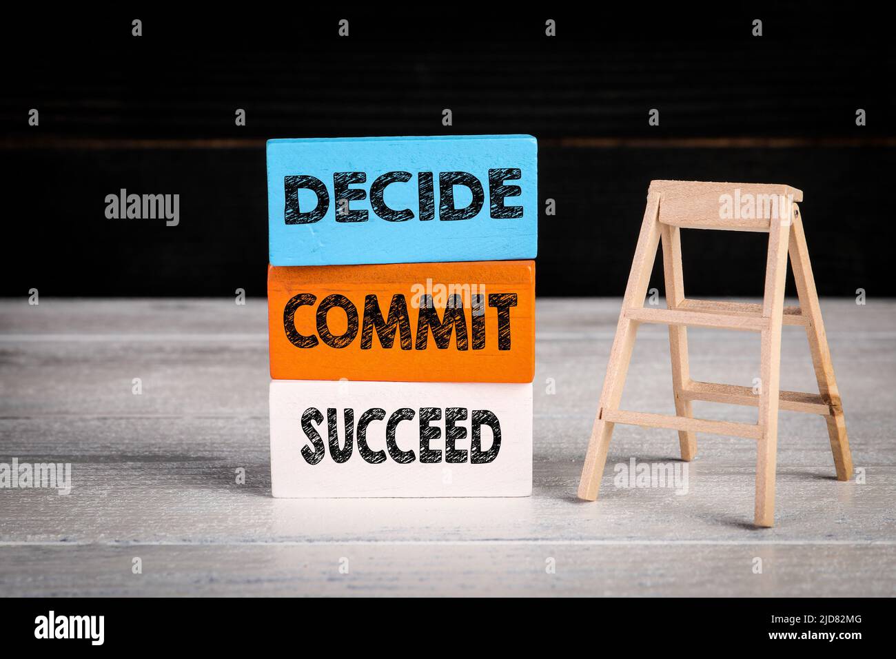 DECIDE COMMIT SUCCEED. Colored wooden blocks and stairs on a white and ...