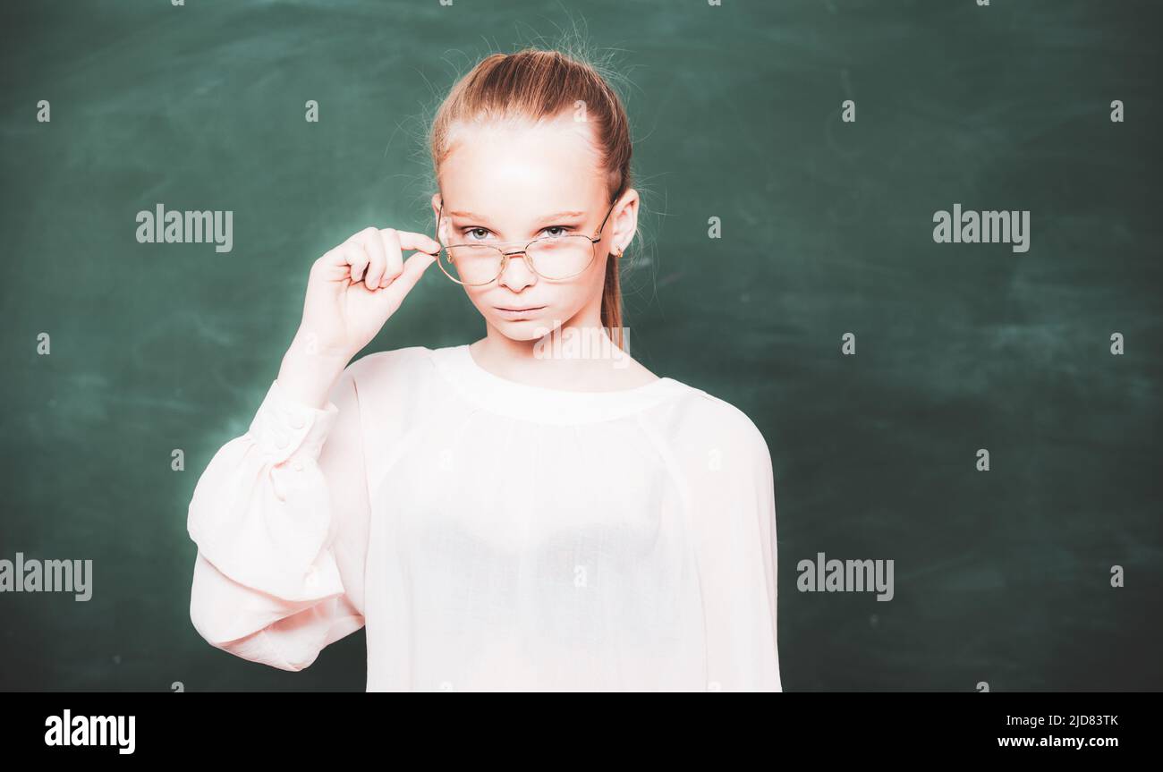 Funny teen student. Young girl standing against blackboard. Portrait of ...