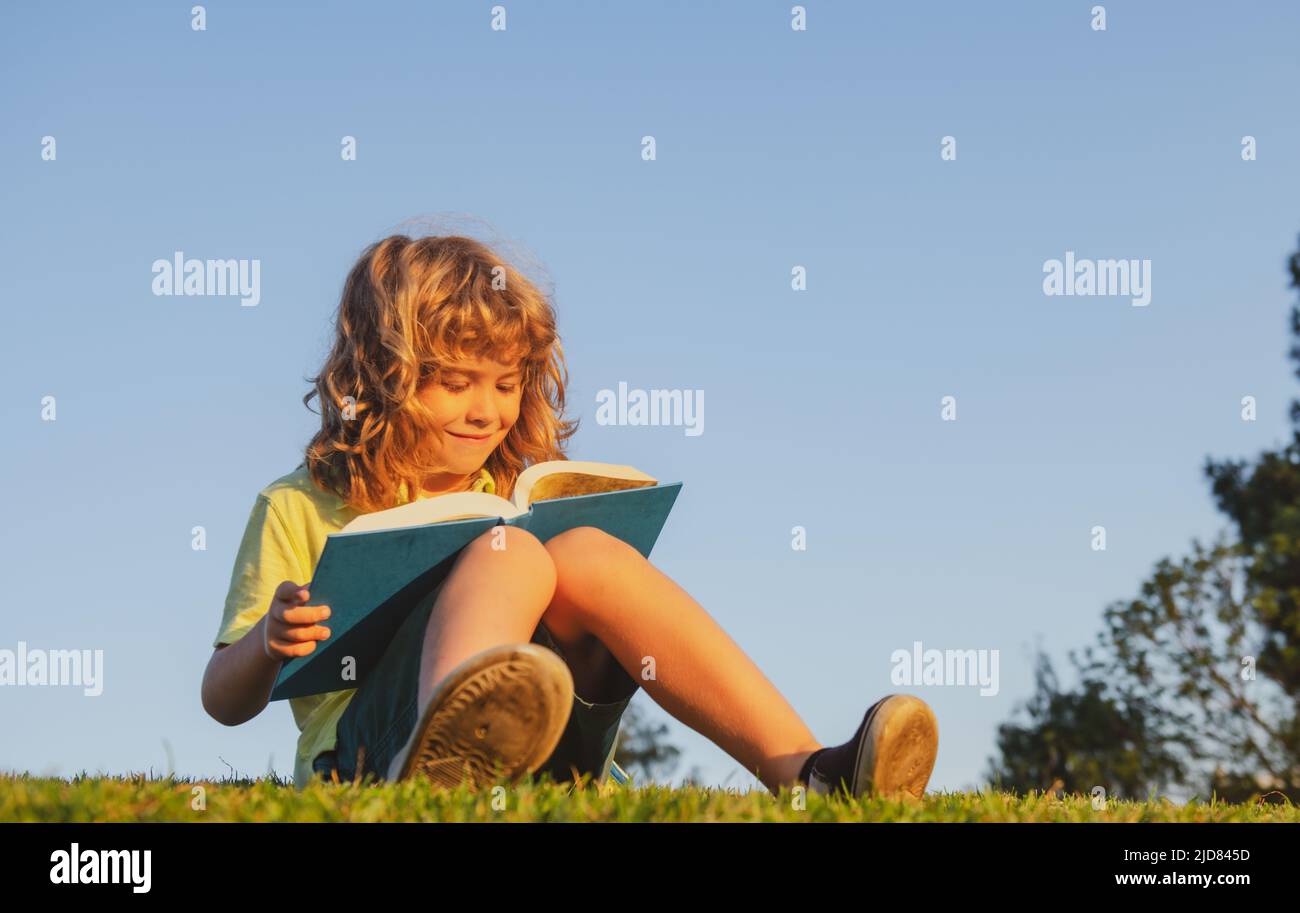 Smart kid boy reading book in park outdoor Stock Photo - Alamy