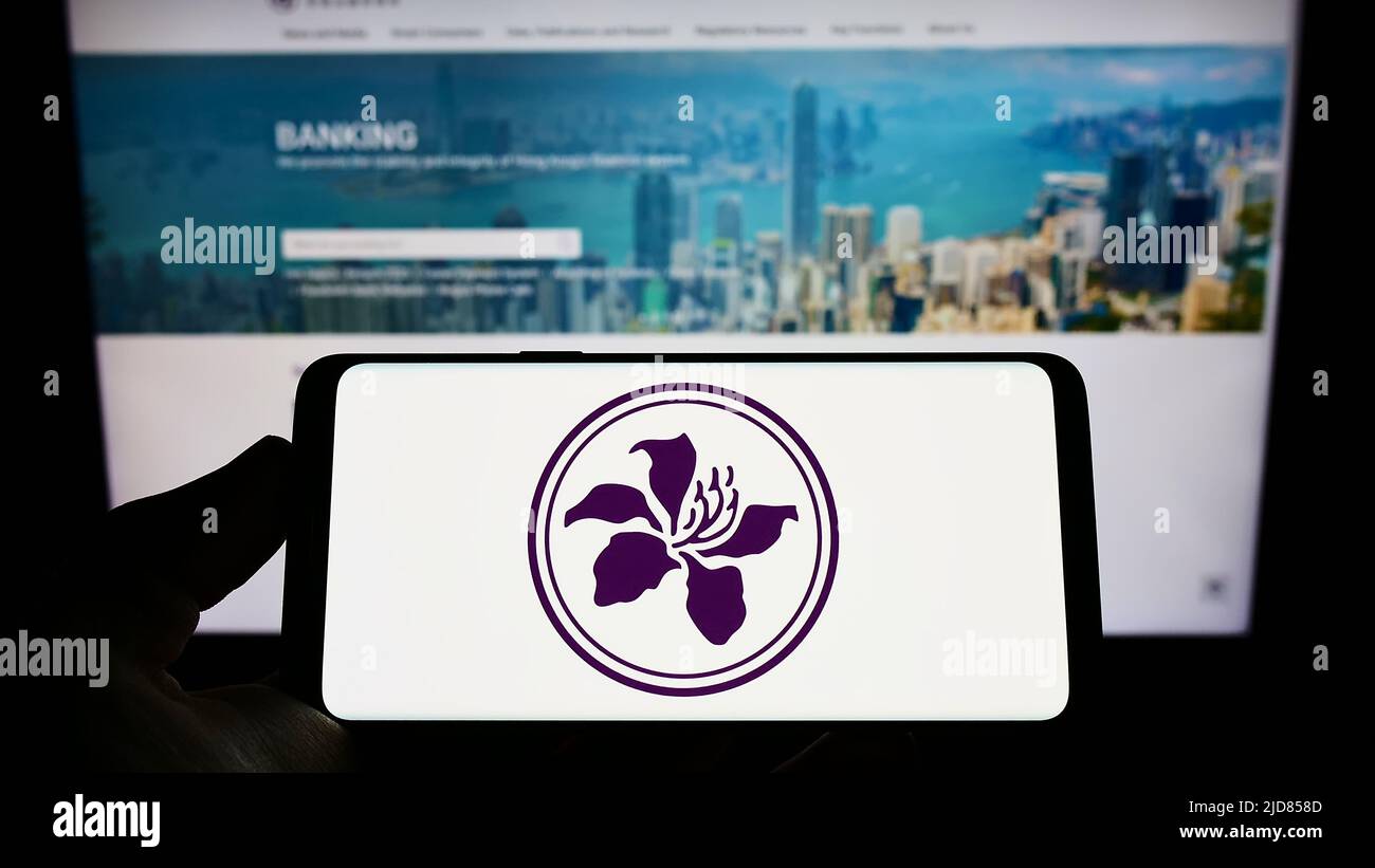 Person holding smartphone with logo of Hong Kong Monetary Authority ...