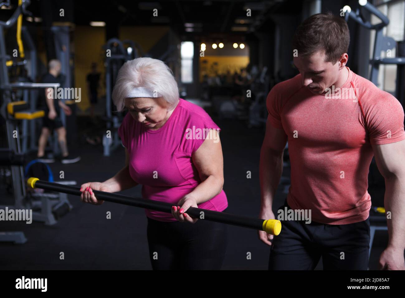Healthy senior woman exercising with personal trainer, doing bicep ...