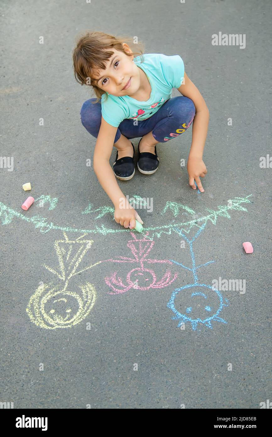 Child draws a family on the pavement with chalk. Selective focus Stock ...