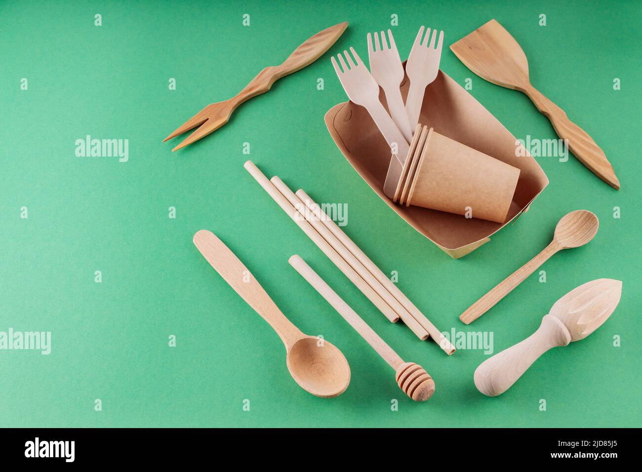 Paper biodegradable tableware and wooden cutlery on a green background ...