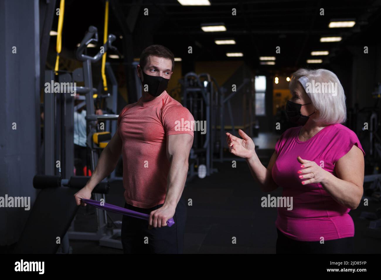 Personal trainer and his senior female client wearing medical face ...