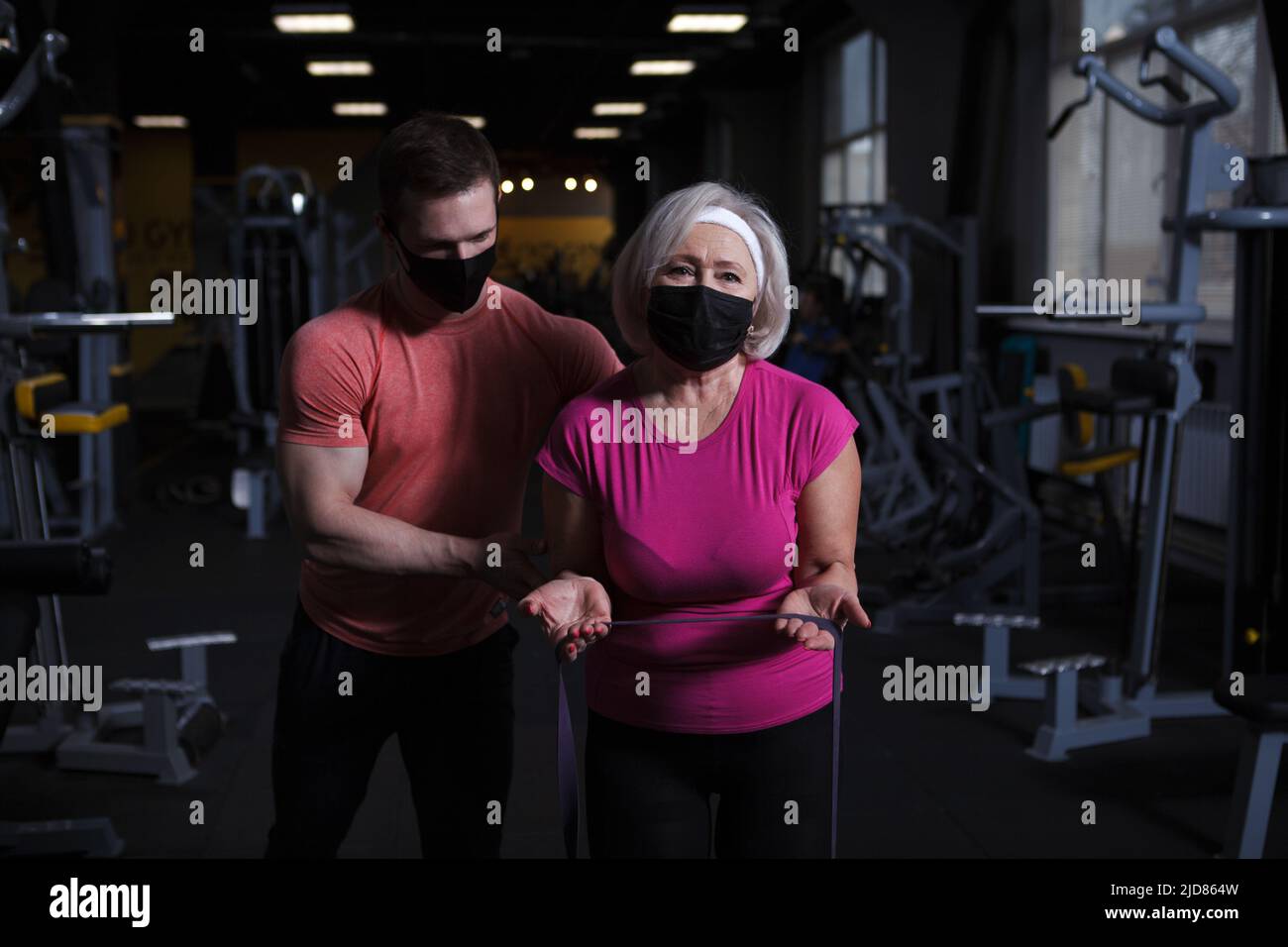 Muscular fitness coach and his senior client wearing medical face masks ...
