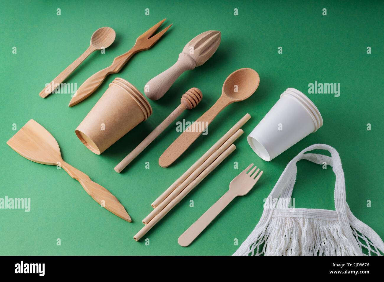 Wooden cutlery and shopping bag on a green background. Eco-friendly ...