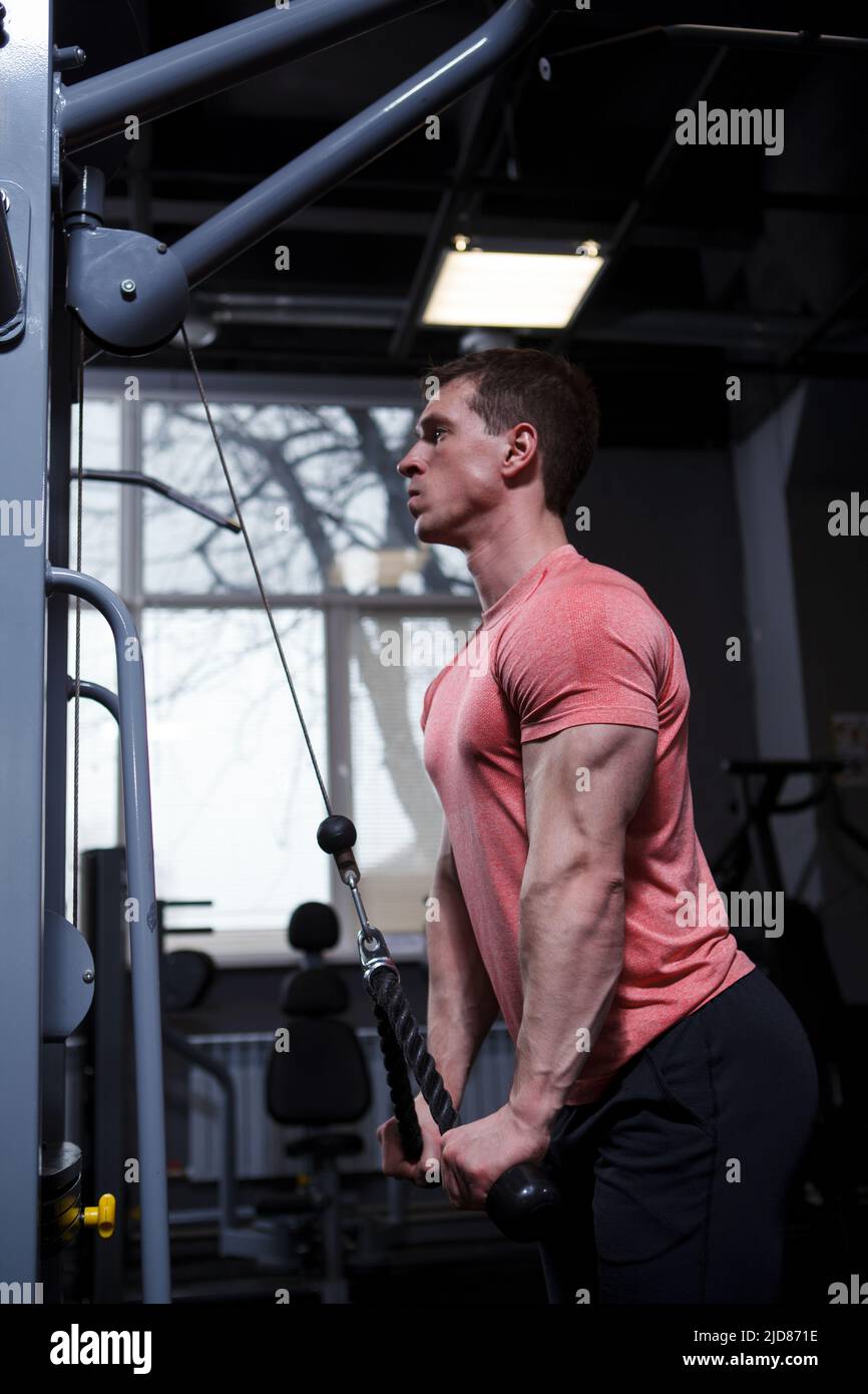 Vertical shot of a muscular man exercising in cable crossover gym ...