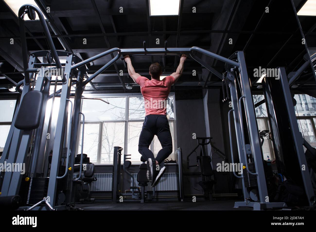Rear view fulllength shot of an athletic muscular man doing pull-ups in ...