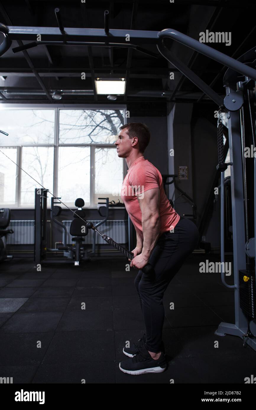 Full length shot of a sportsman doing back muscles exercise in cable ...