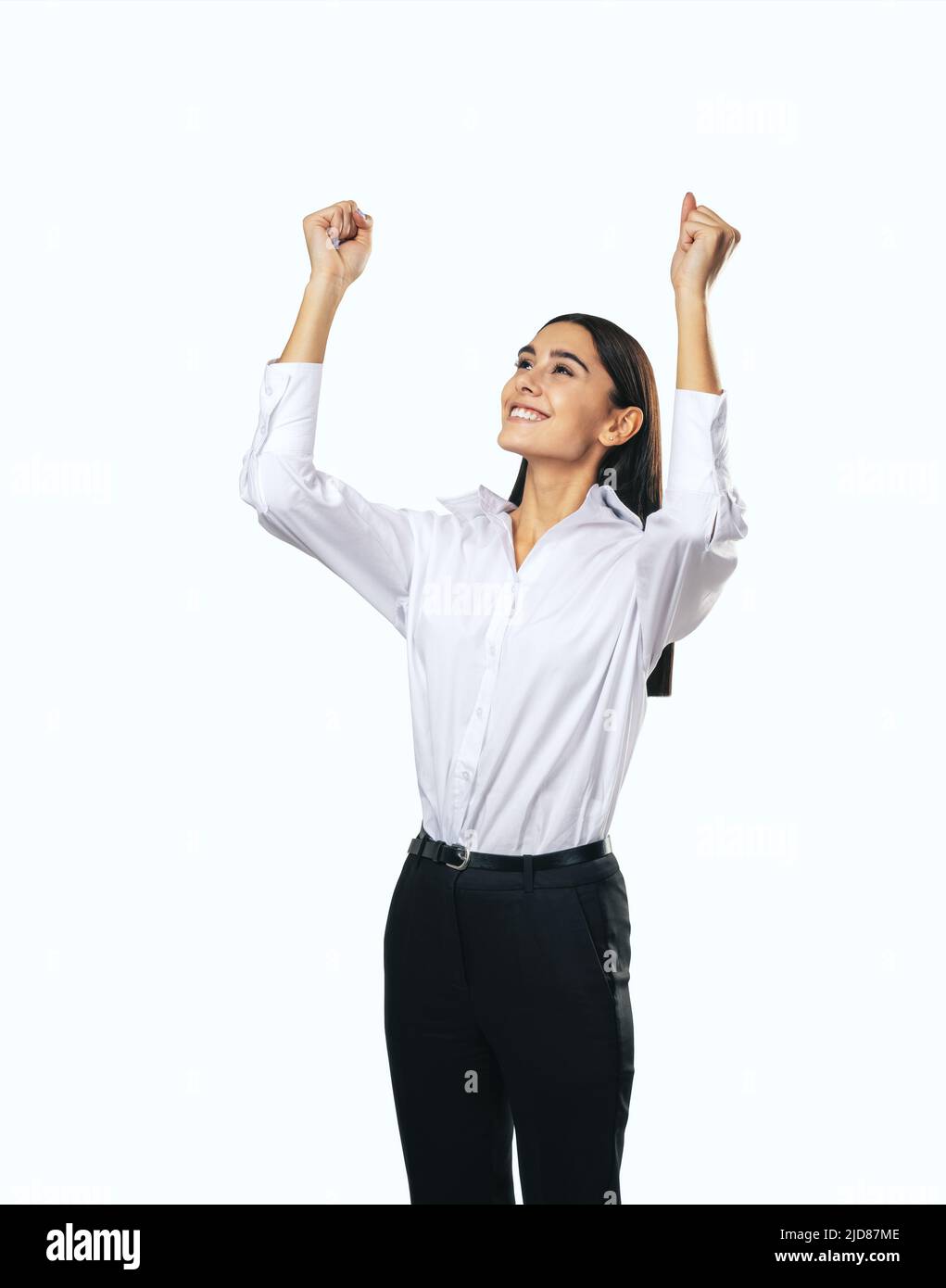 Joyful and satisfied woman in white shirt with raised hands showing her ...