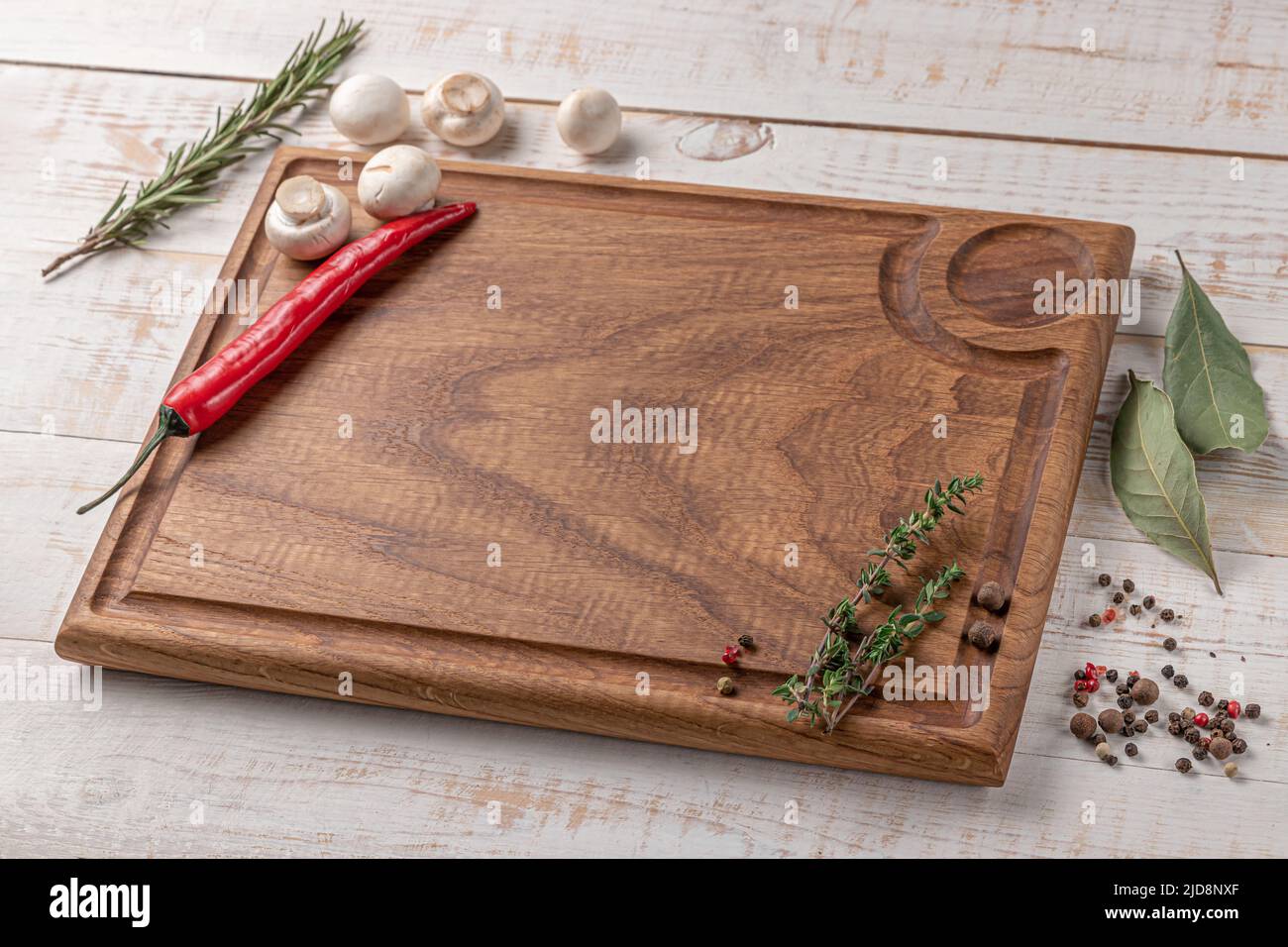 square wooden cutting board of dark color with edging. mushrooms, chili ...