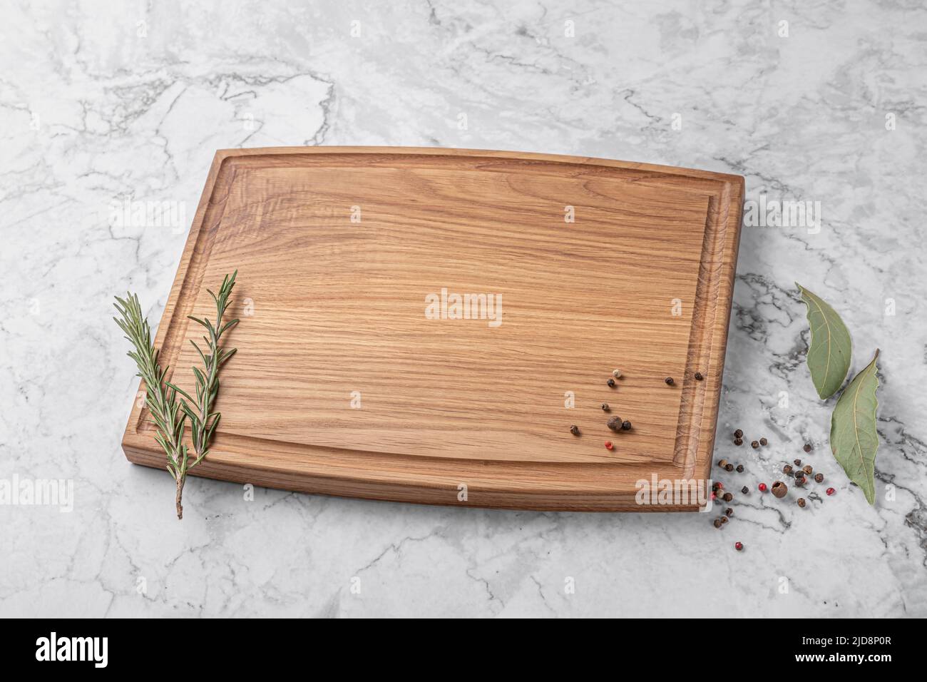 square wooden cutting board with edging. thyme and spices on a white ...
