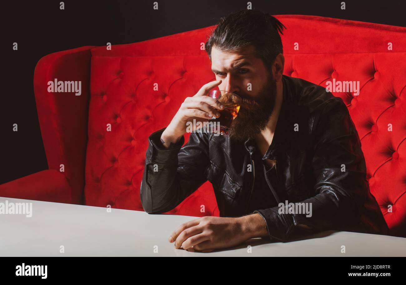 Bearded man drinking whisky, whiskey or cognac brandy. Hipster brutal ...
