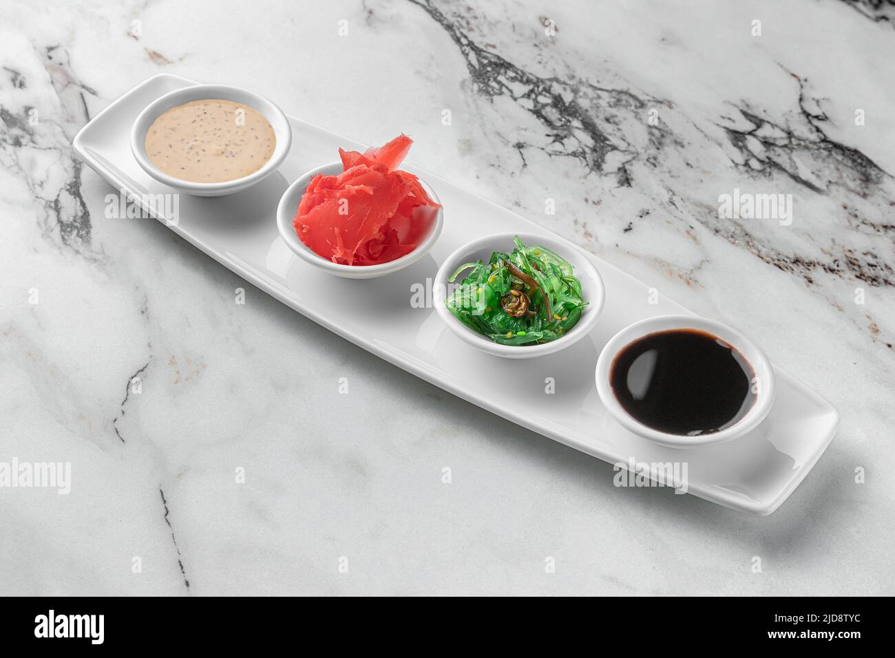 set of sauces for sushi on a white plate, ginger, soy, sesame, seaweed ...