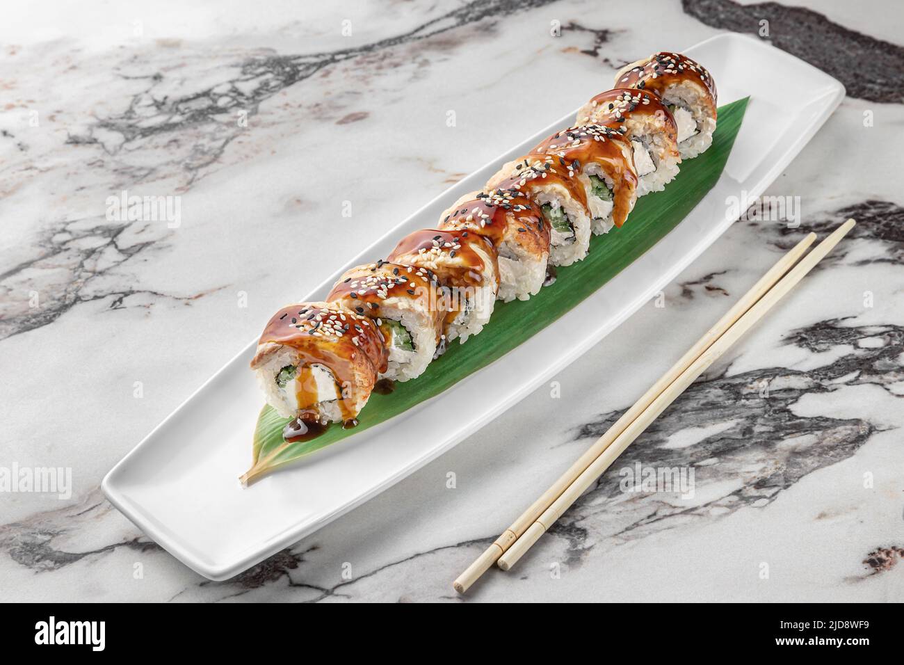 set of philadelphia rolls with eel and green bamboo leaf in a white ...