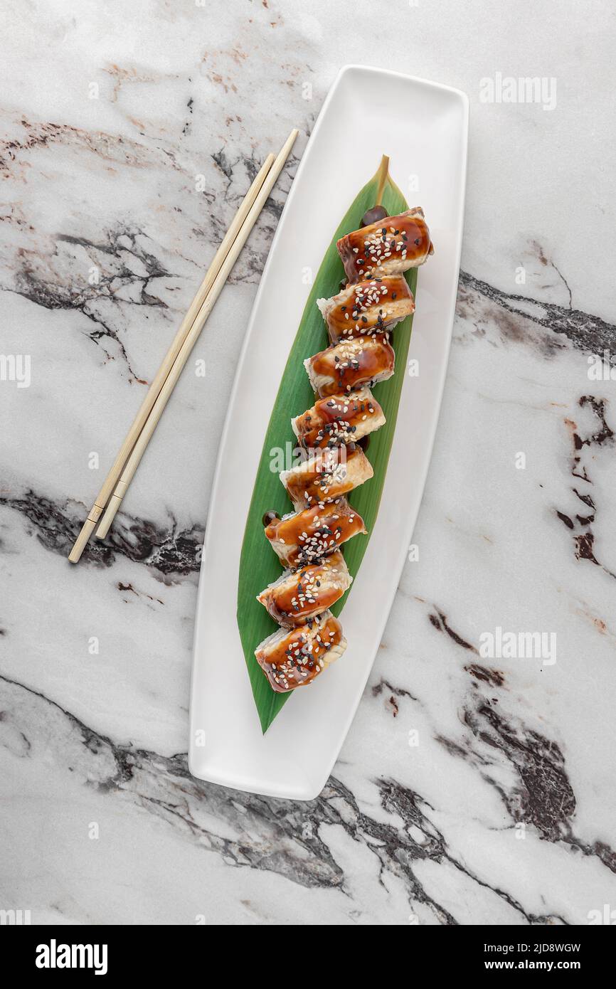 set of philadelphia rolls with eel and green bamboo leaf in a white ...