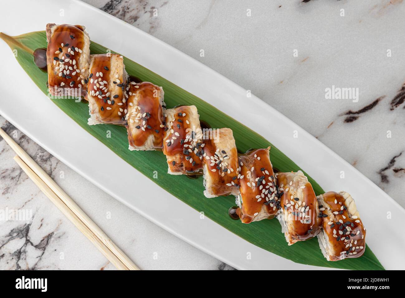 set of philadelphia rolls with eel and green bamboo leaf in a white ...