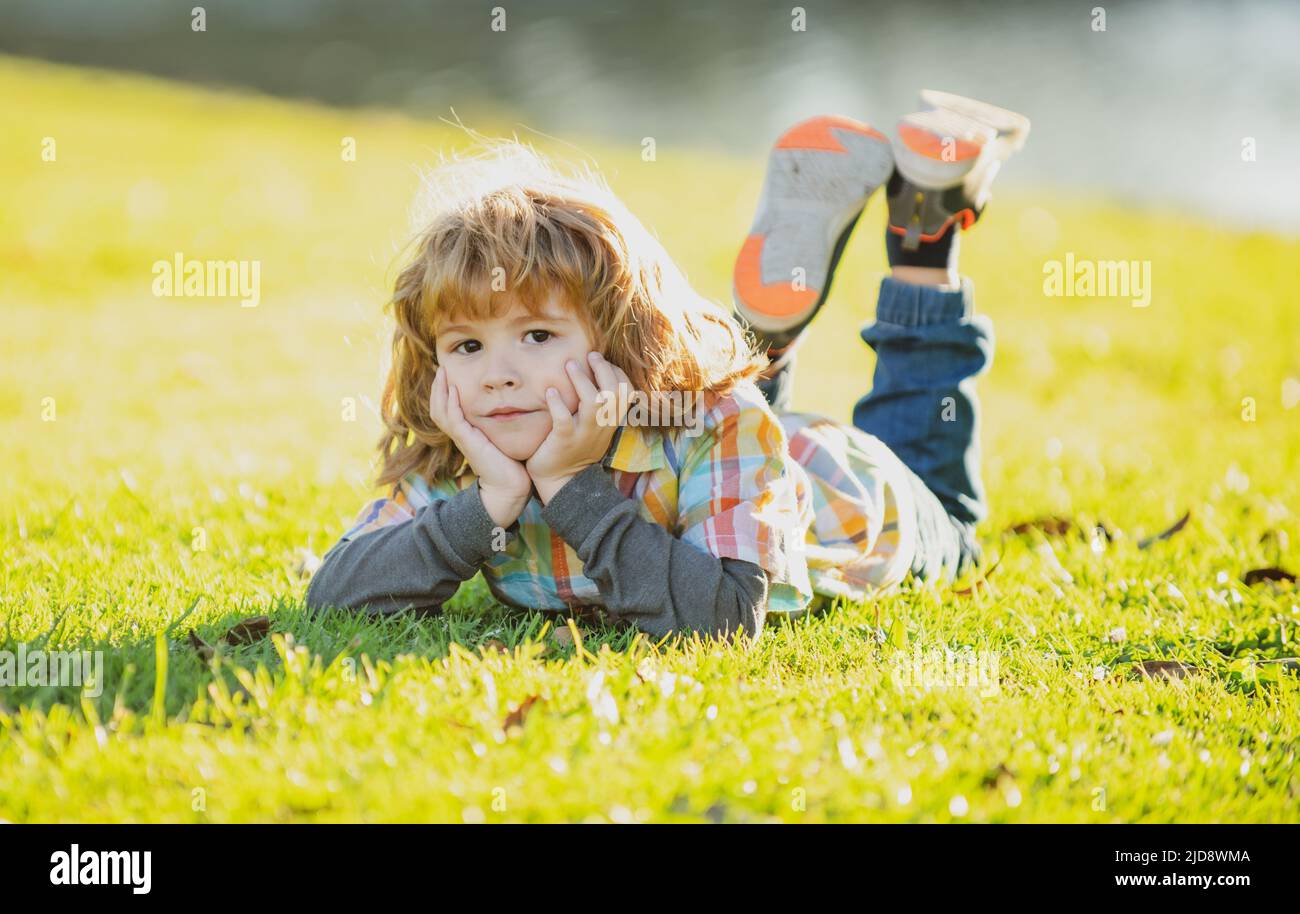 Child in park outdoor. Spring kid lying on grass. Summer boy walk ...