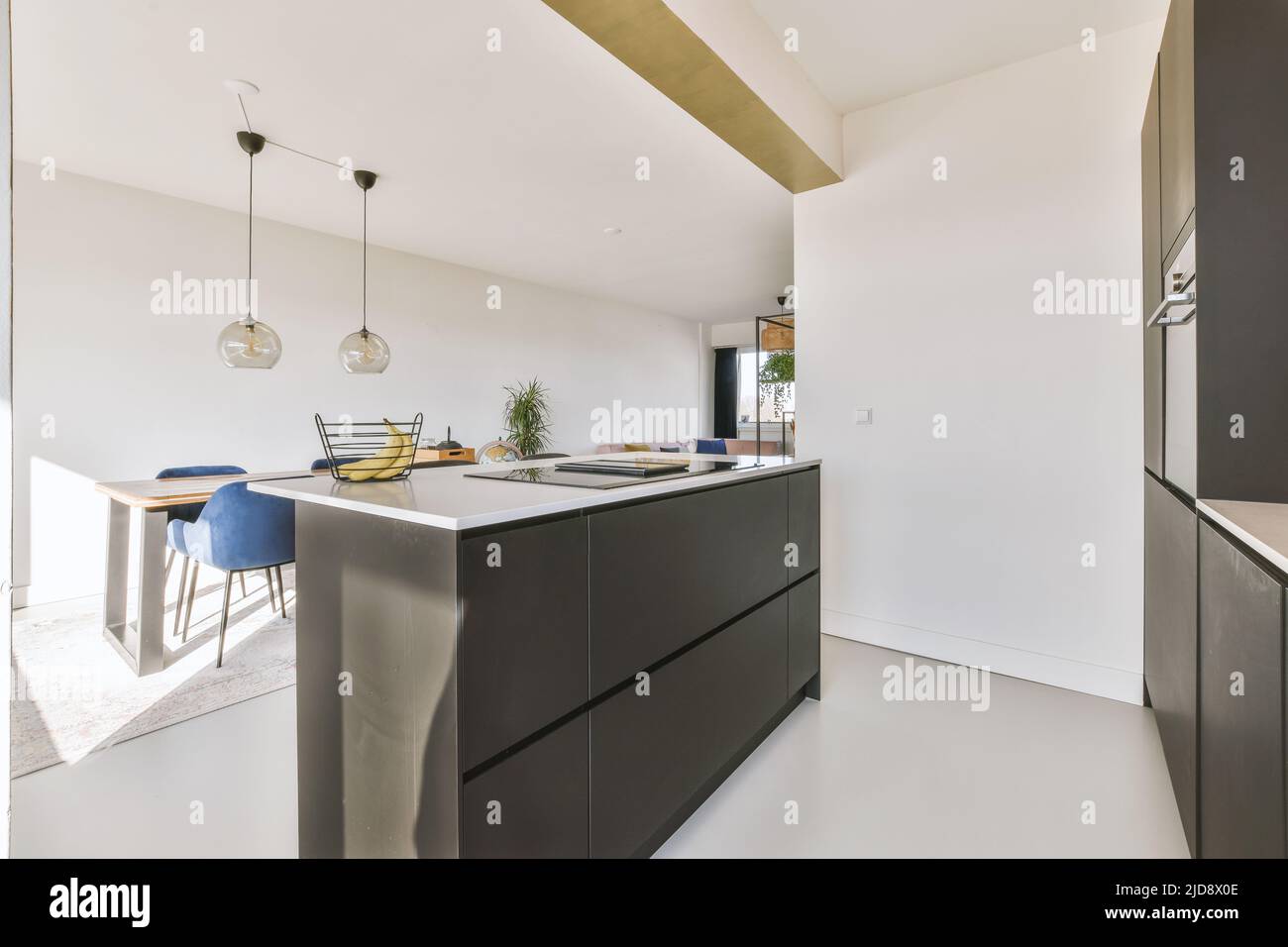 Wooden dining table under pendant lamp in open plan kitchen with living ...