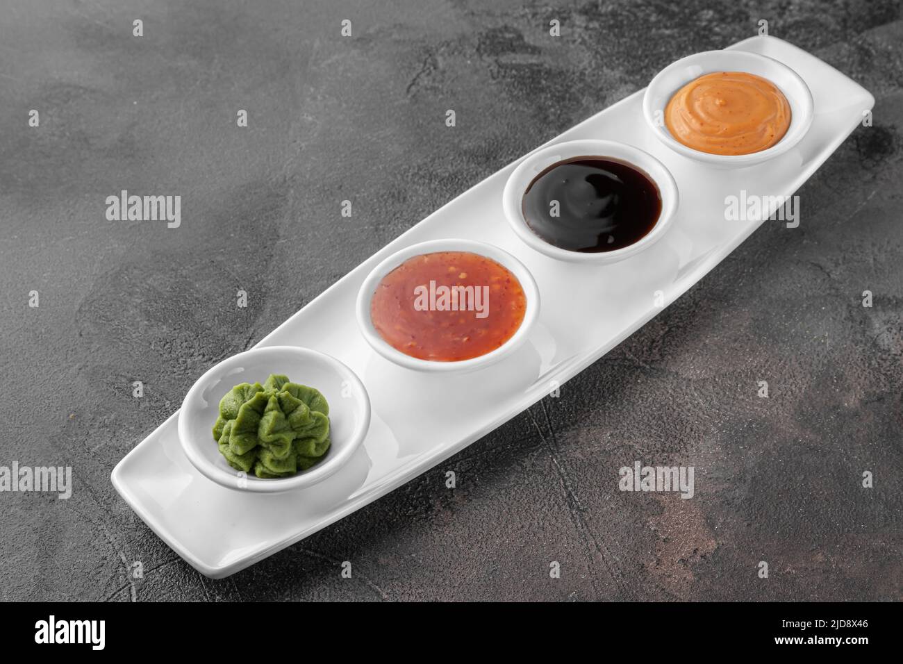 set of sauces for sushi on a white plate, wasabi, spicy, cheesy, soy ...